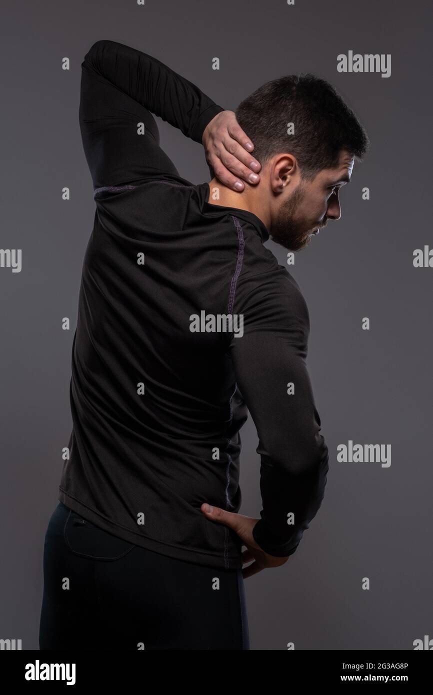 Rear view of athletic man stretching on grey background Stock Photo - Alamy