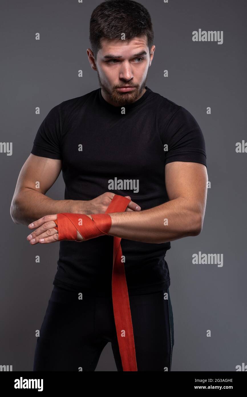 Young kickboxer wrapping bandages on hands before training Stock Photo ...