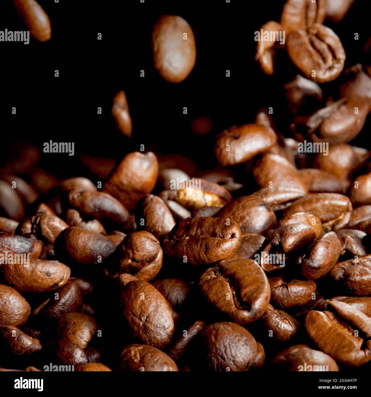 Roasted coffee beans falling down black background Stock Photo - Alamy