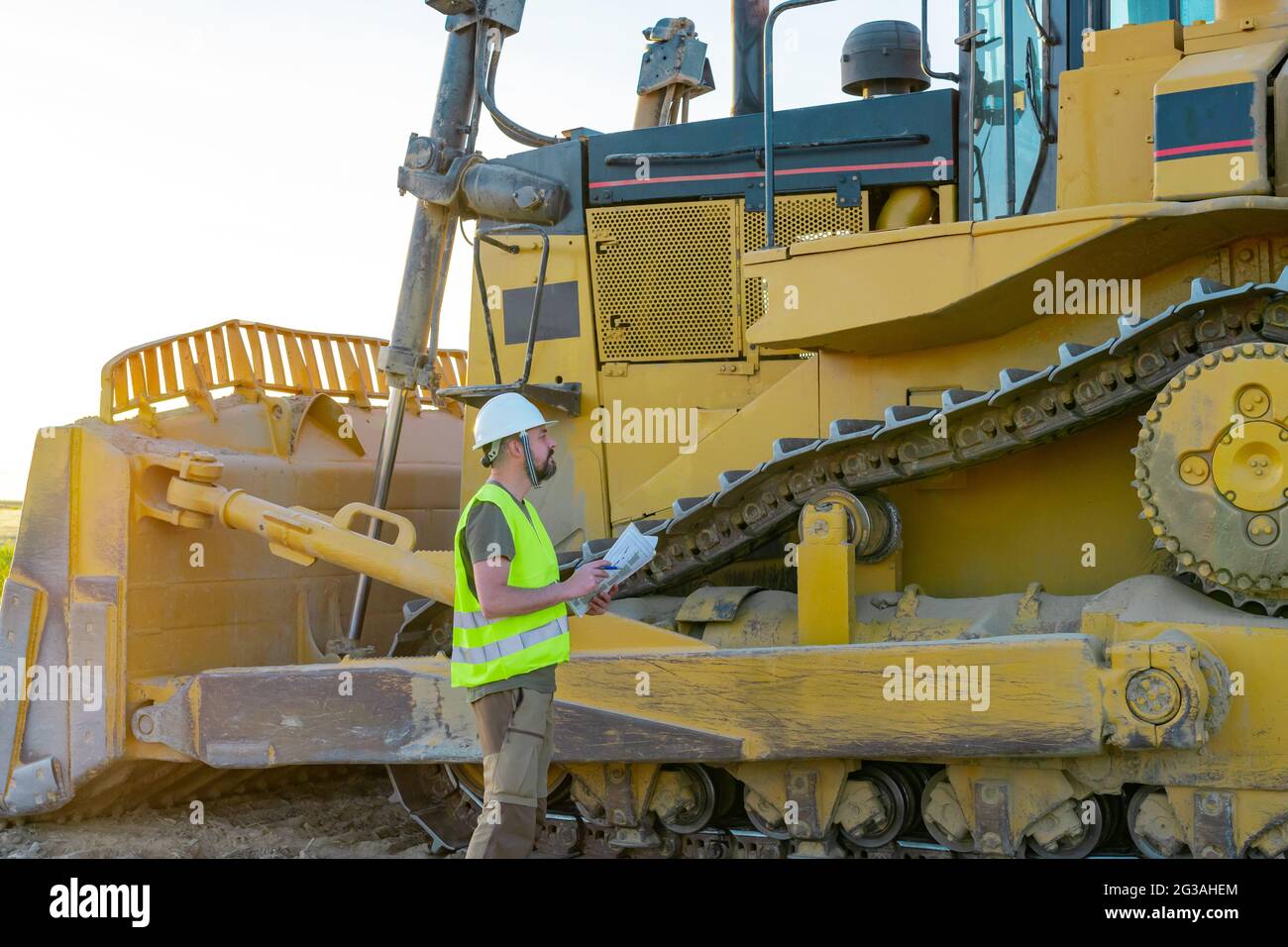 Hipster construction manager with a beard and safety helmet inspects a ...
