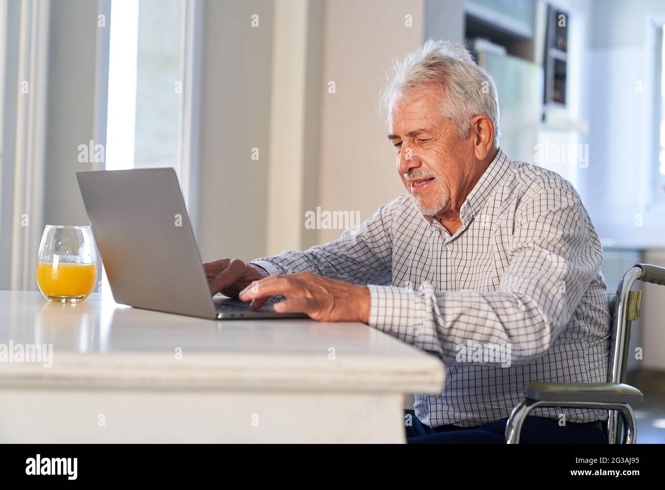Senior at home using laptop computer is typing email or chatting online ...