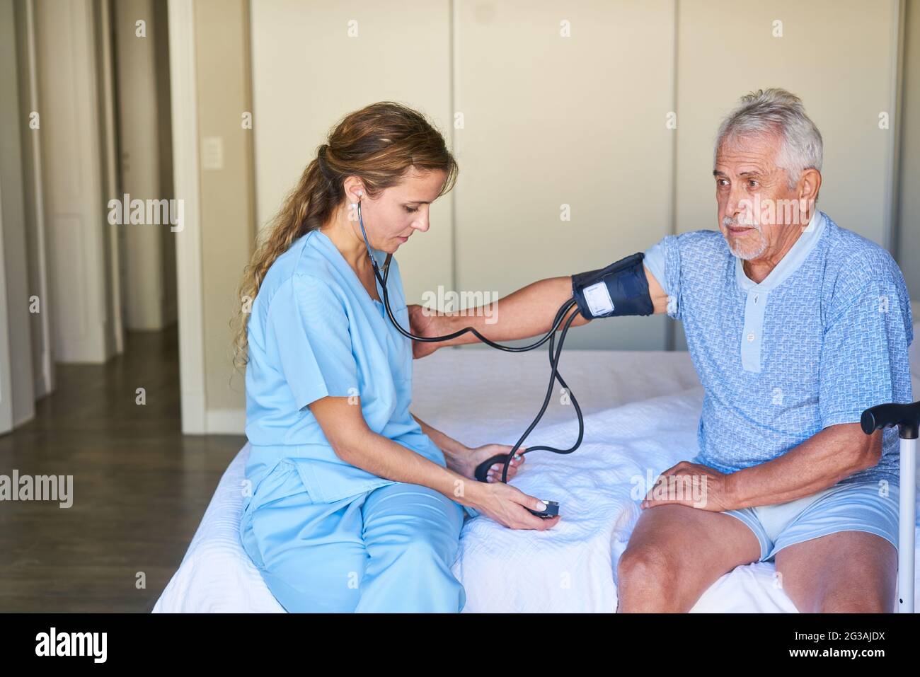 Geriatric nurse measures the blood pressure of a senior patient in a ...