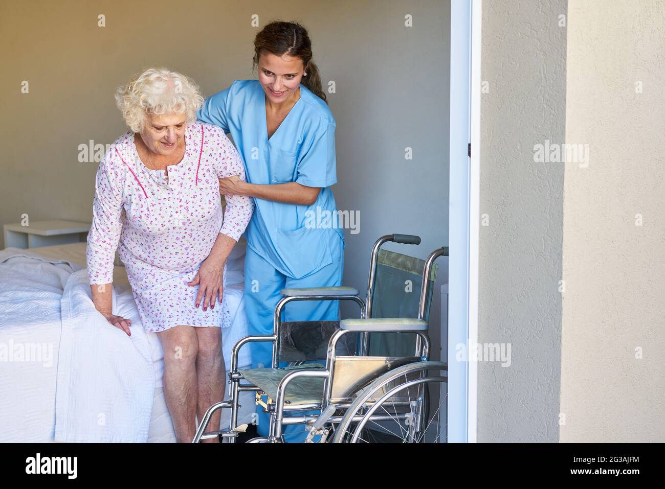 Nursing assistant or geriatric nurse helps senior citizen in bed to get ...