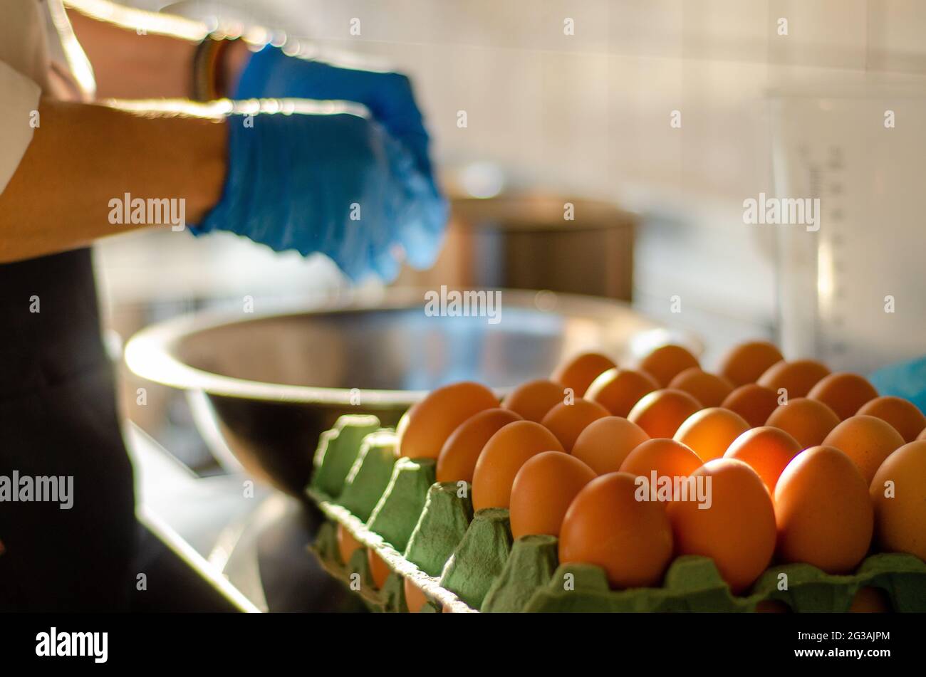 Blurry view of chef hands cracking eggs on the professional stainless steel kitchen table Stock ...