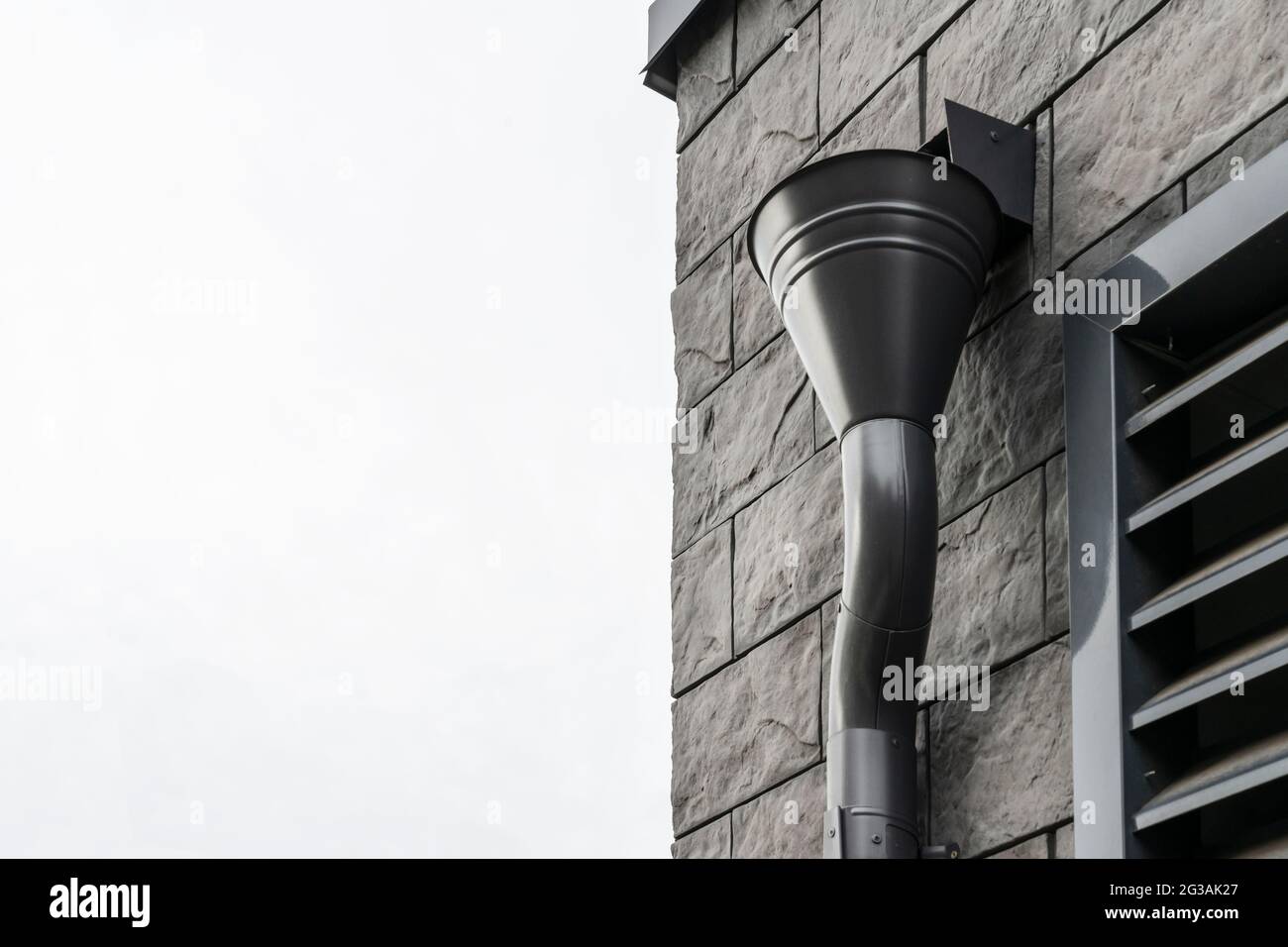 roof gutter mounted on the wall of the building lined with modern stone ...