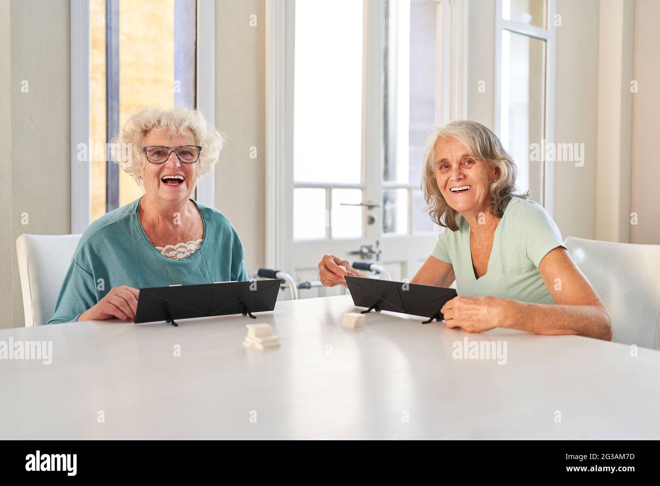 Senior women have fun together playing Rummikub as brain jogging and ...