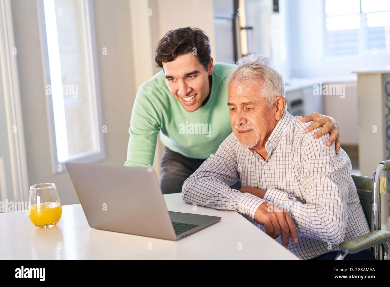 Son supports his father on the laptop computer at home while chatting ...