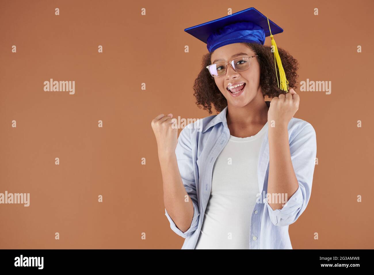 Portrait of cheerful mixed race high school graduate in academic cap ...