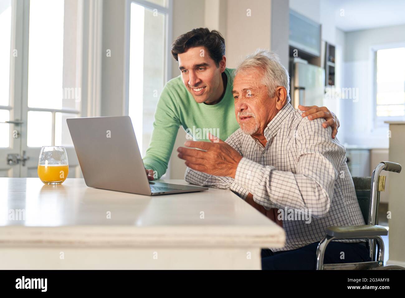 Curious senior father is supported by his son while chatting on social ...