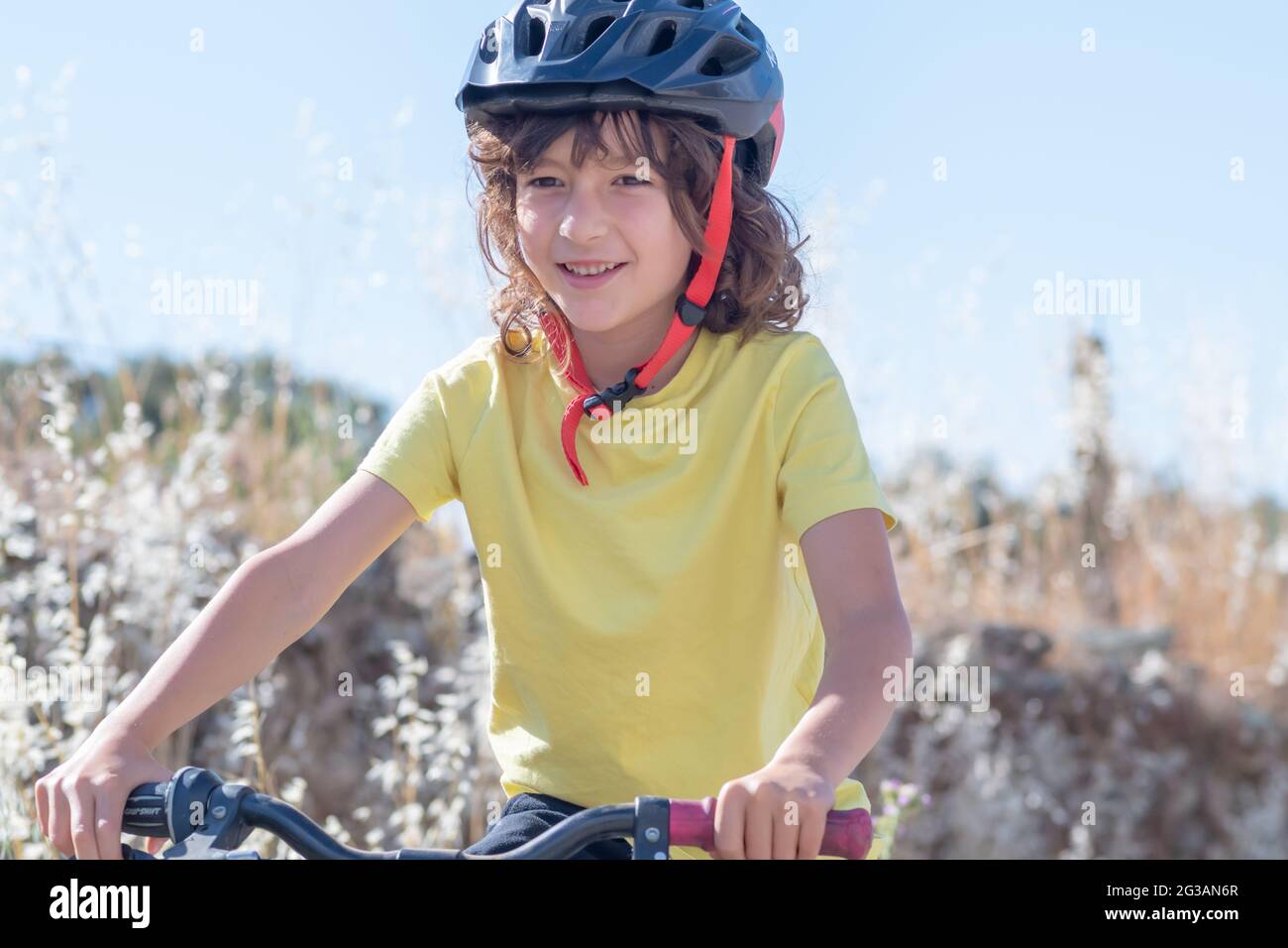 little boy with safety helmet has fun and smiles while riding his bike ...