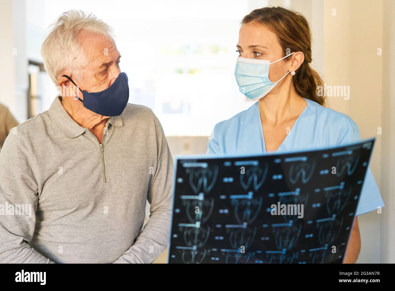 Female doctor and a senior patient with face mask discuss an MRI scan ...