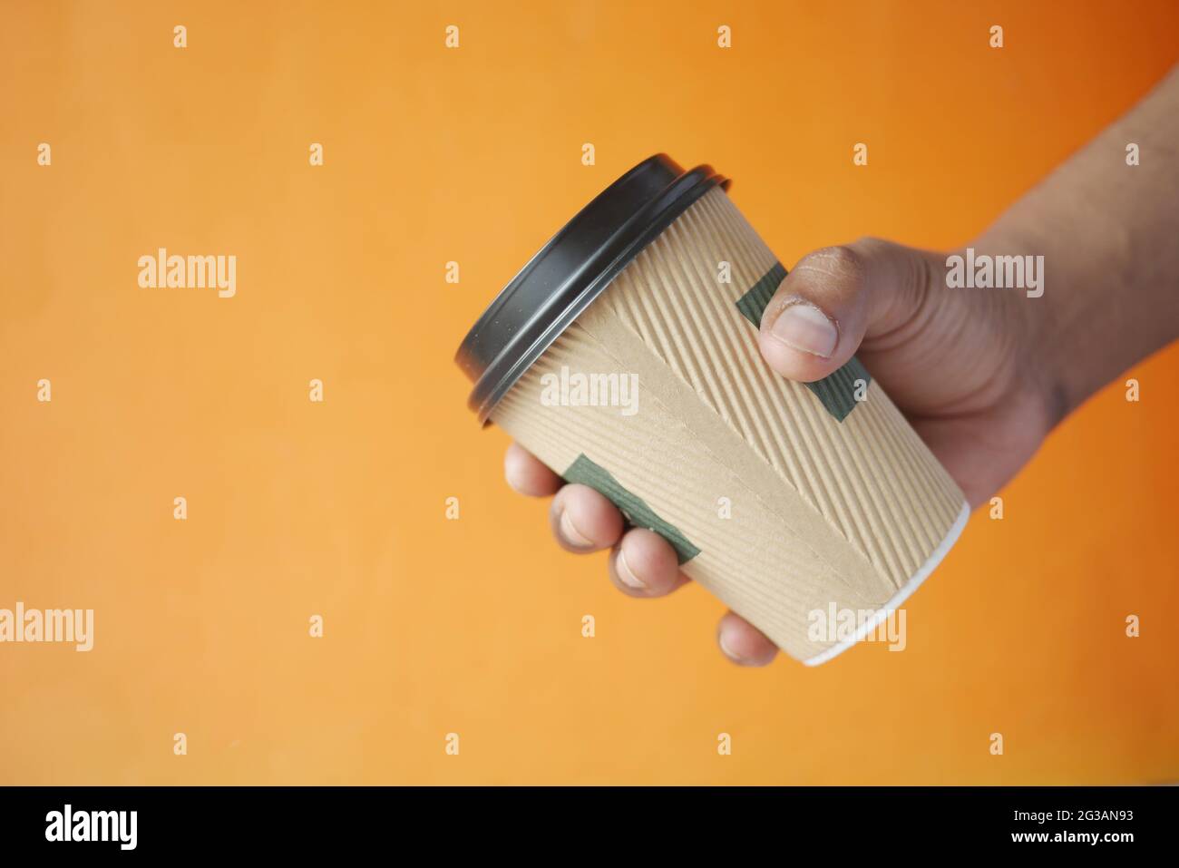 hand holding take away paper cup against orange background Stock Photo ...