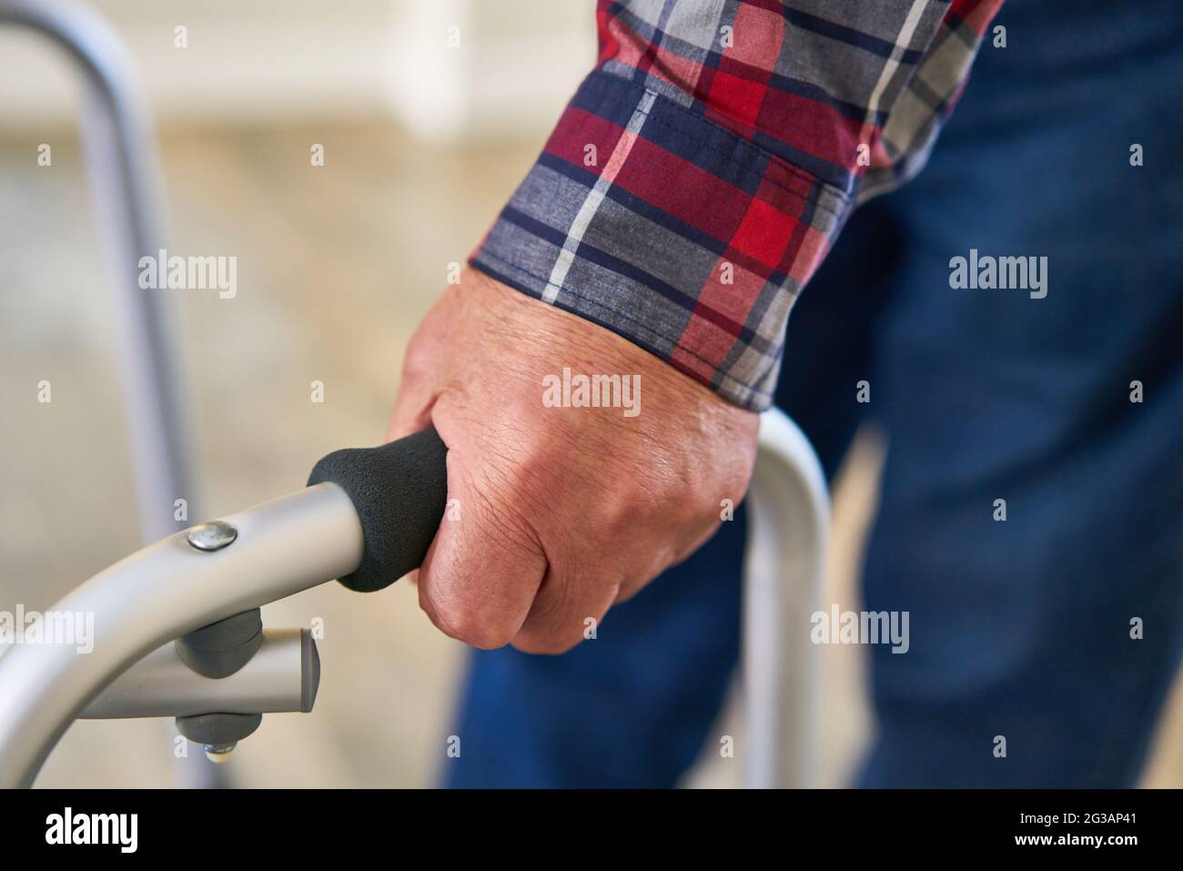 Hand of a senior patient after a stroke includes the handle of a walker ...