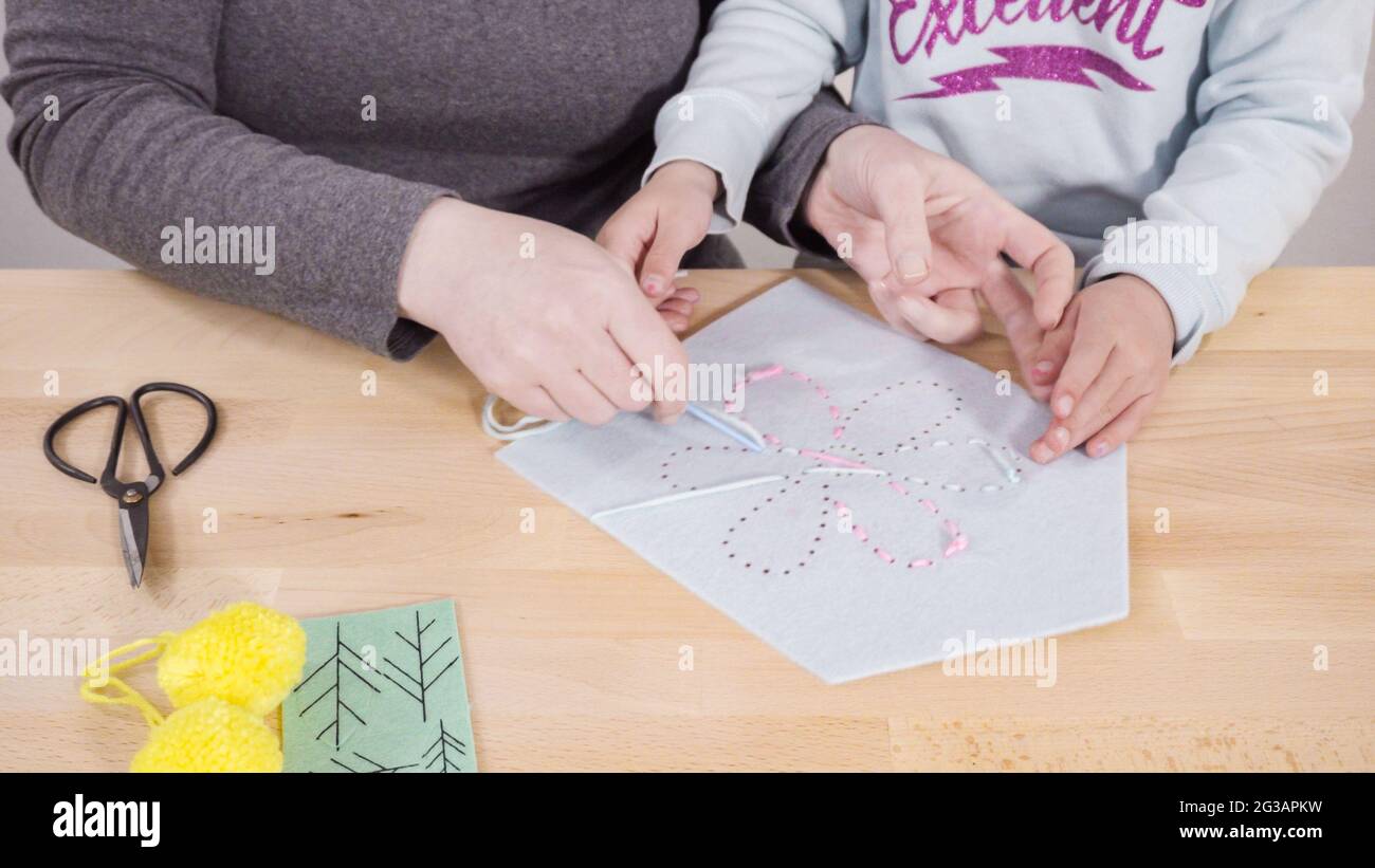 Little girl learning how to sew with her mother at the craft table ...