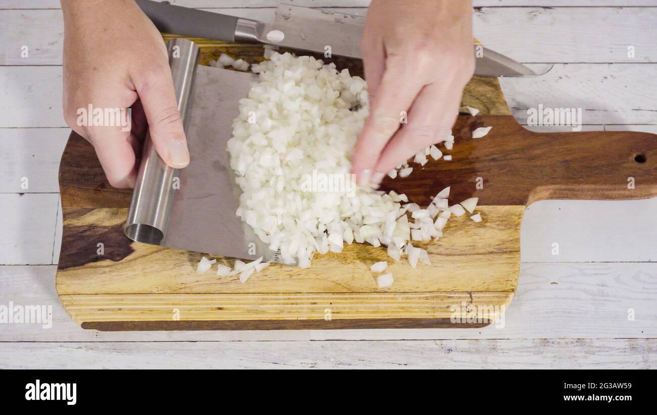 Mincing organic yellow onion on a wood cutting board Stock Photo - Alamy