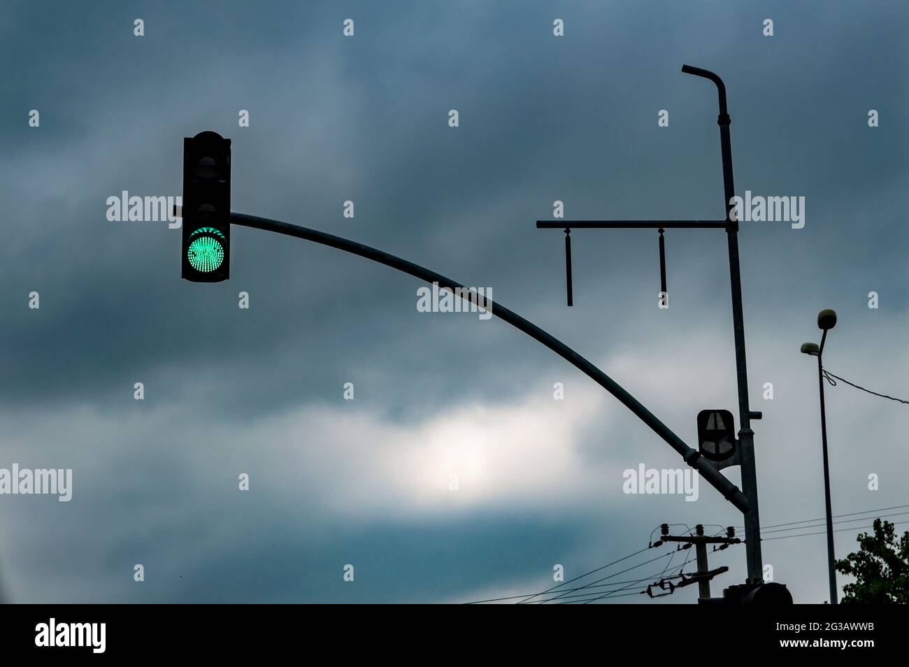 traffic light burning green on the dark clouds background. traveling ...