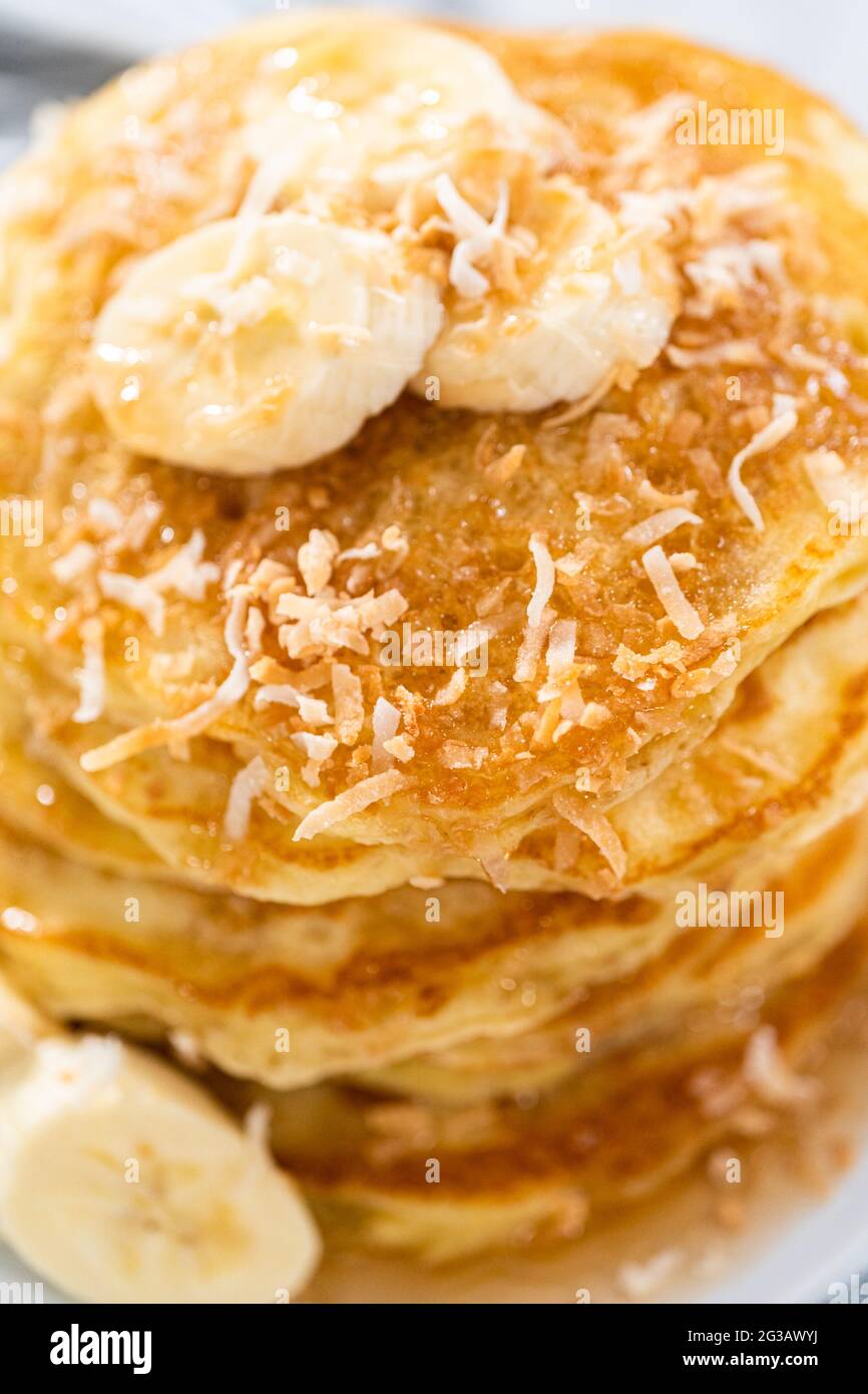 Stack of freshly baked coconut banana pancakes garnished with sliced ...