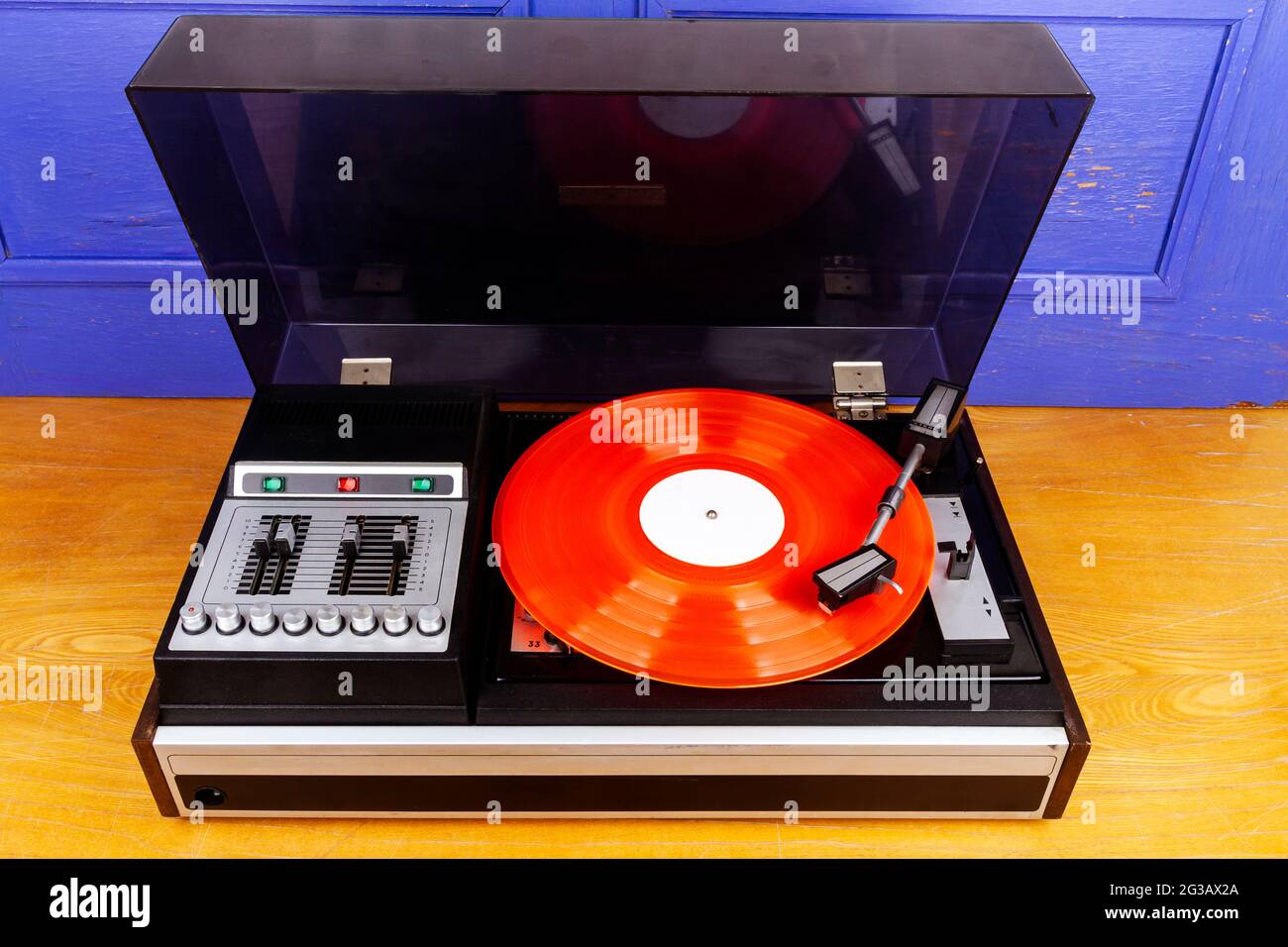 Vintage turntable vinyl record player with red vinyl on table by blue ...