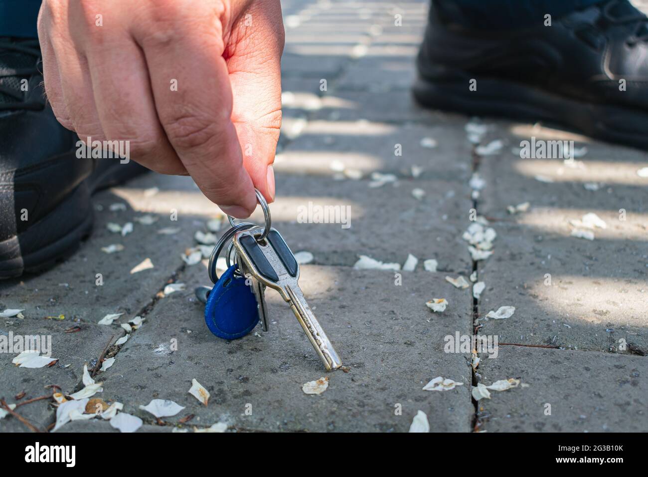 Man picks up a bunch of keys lying on the road Stock Photo - Alamy