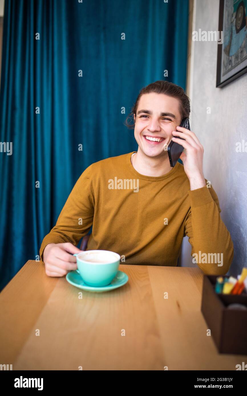 Happy man at coffee shop talking on the phone Stock Photo - Alamy