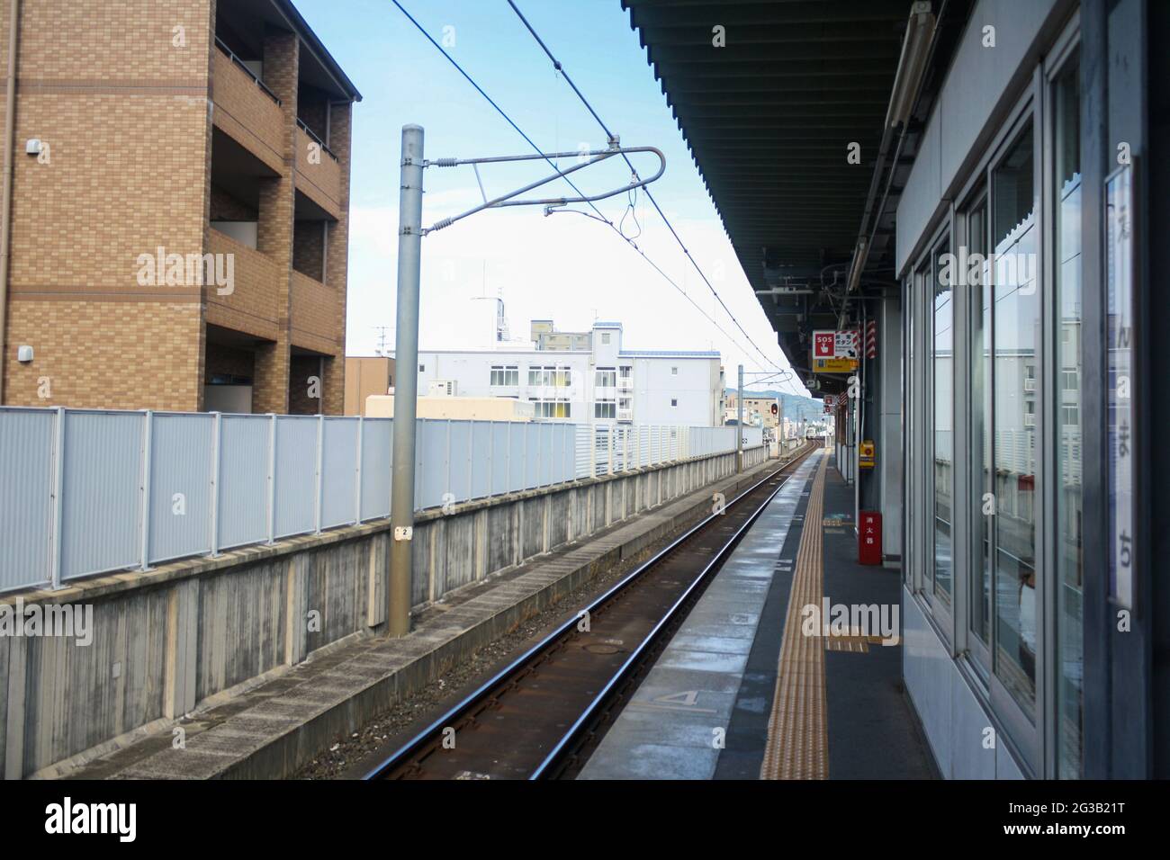 Empty platform and rail track at a small train station. Clouds in blue ...