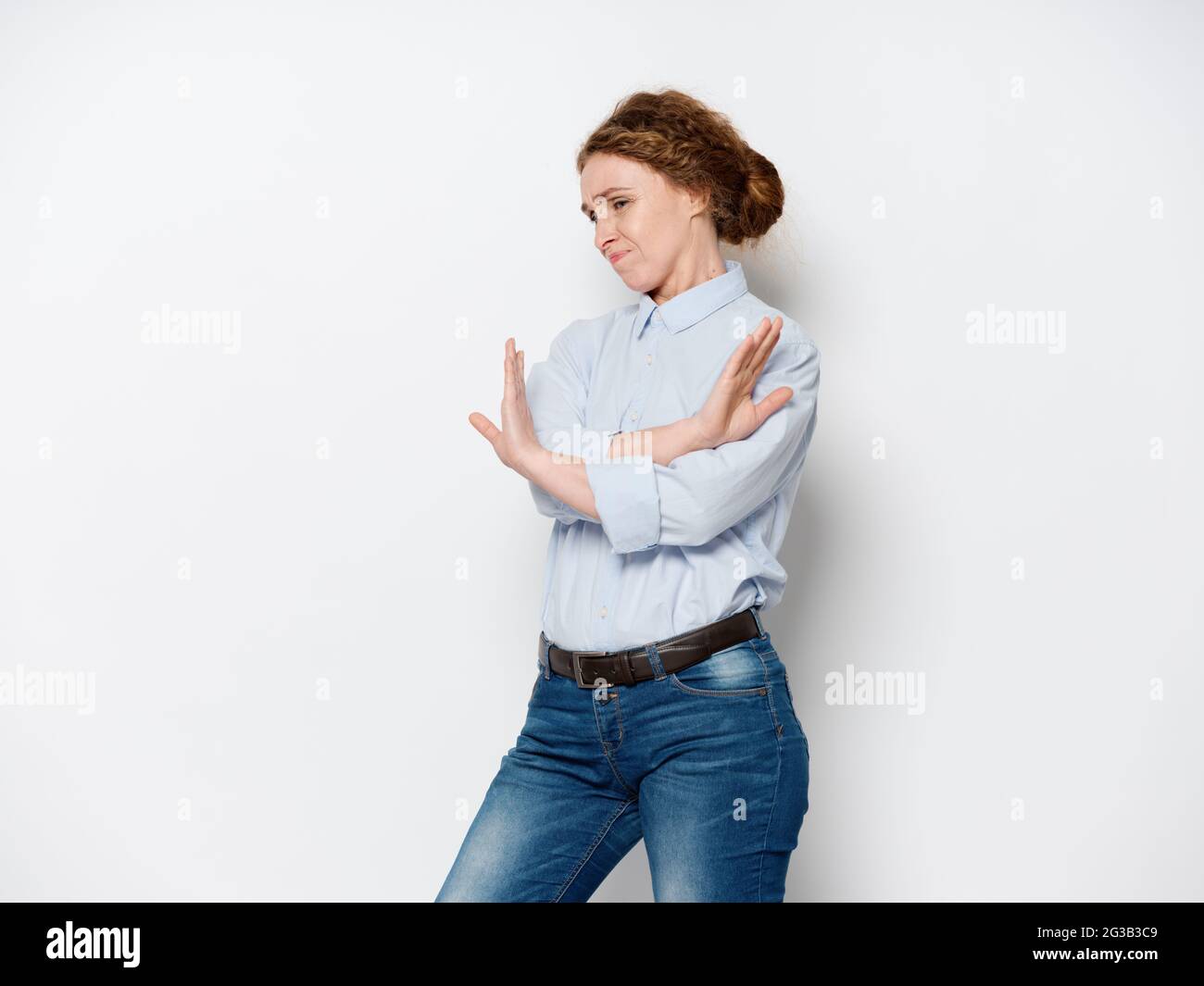 portrait of an elderly woman in a shirt jeans with her arms crossed ...