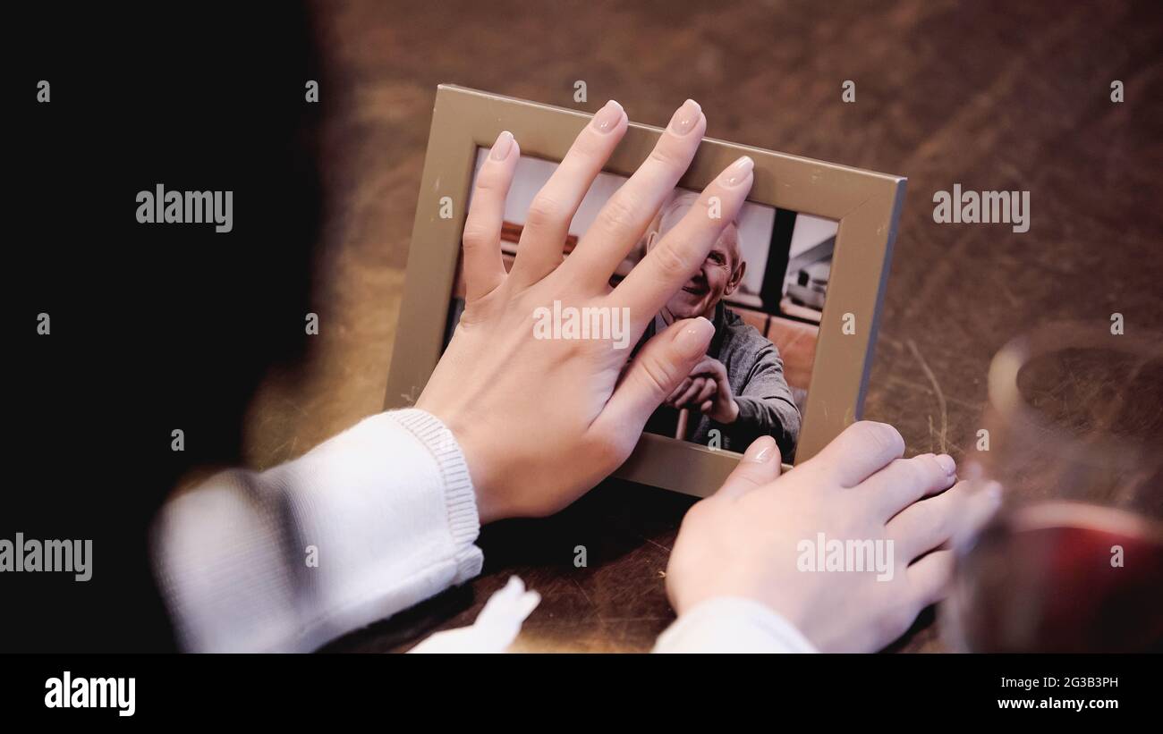 partial view of female hands touching photo frame with picture of ...