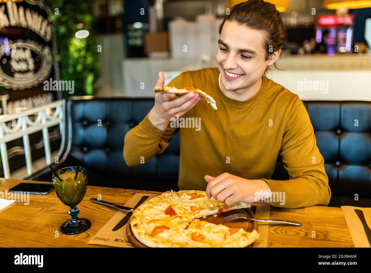 Young happy man eating pizza in cafe Stock Photo - Alamy