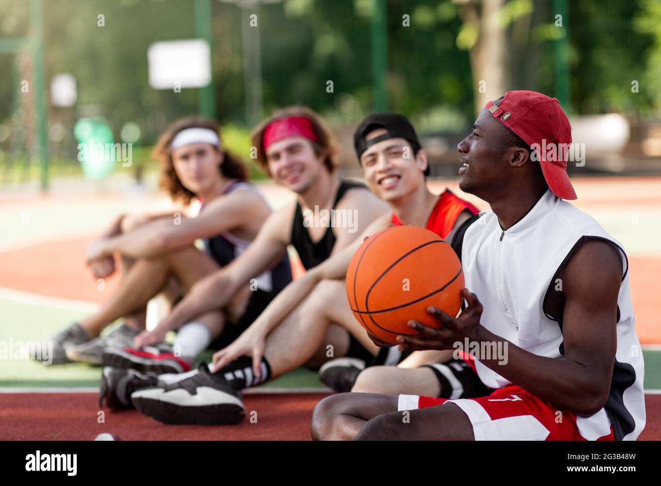 Young African American basketballer and his diverse team relaxing ...