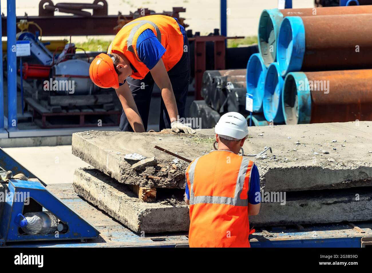 Two slingers unload concrete slabs on the street on a summer day ...