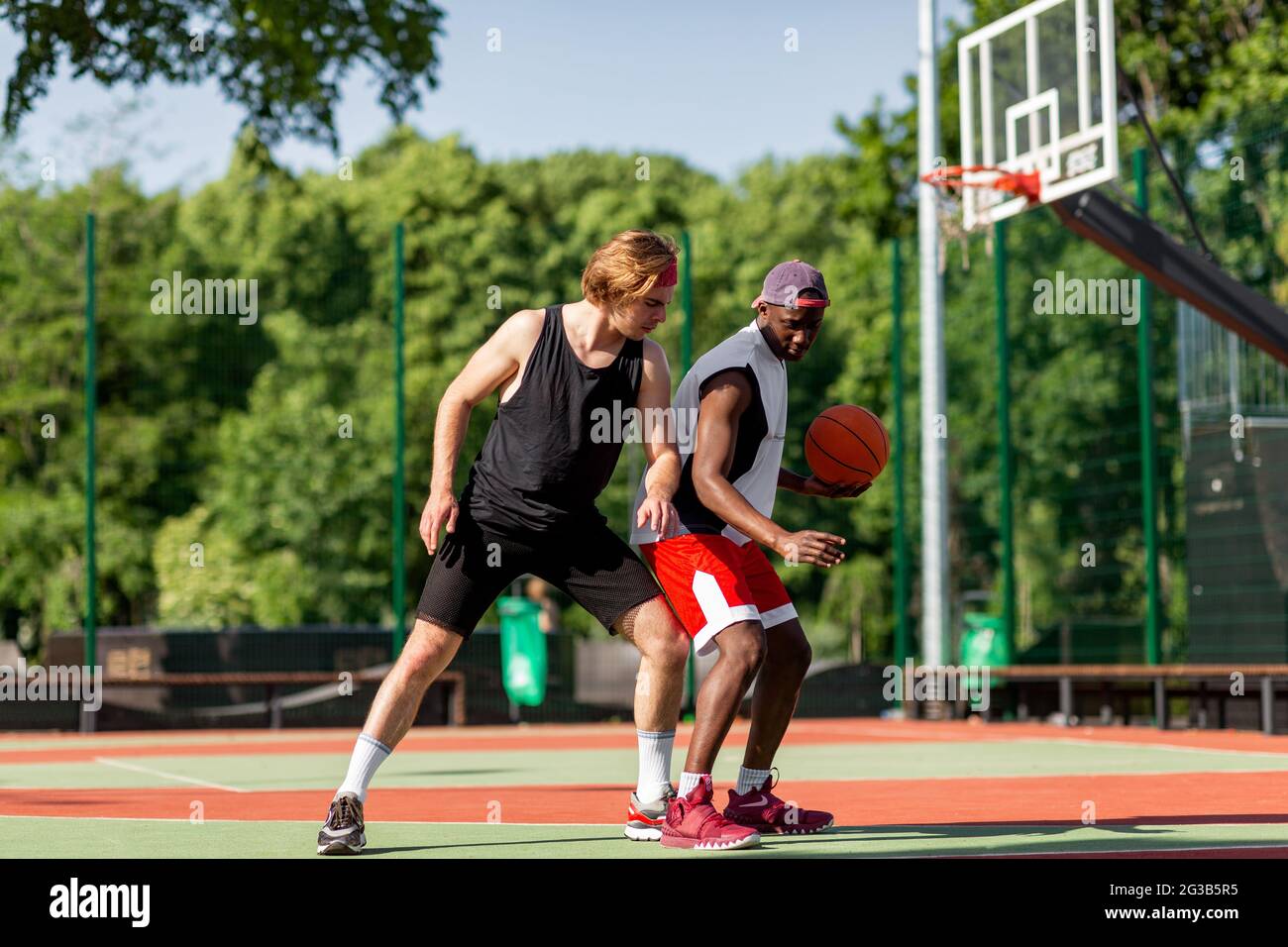 Two young diverse basketball players in action at outdoor sports arena ...