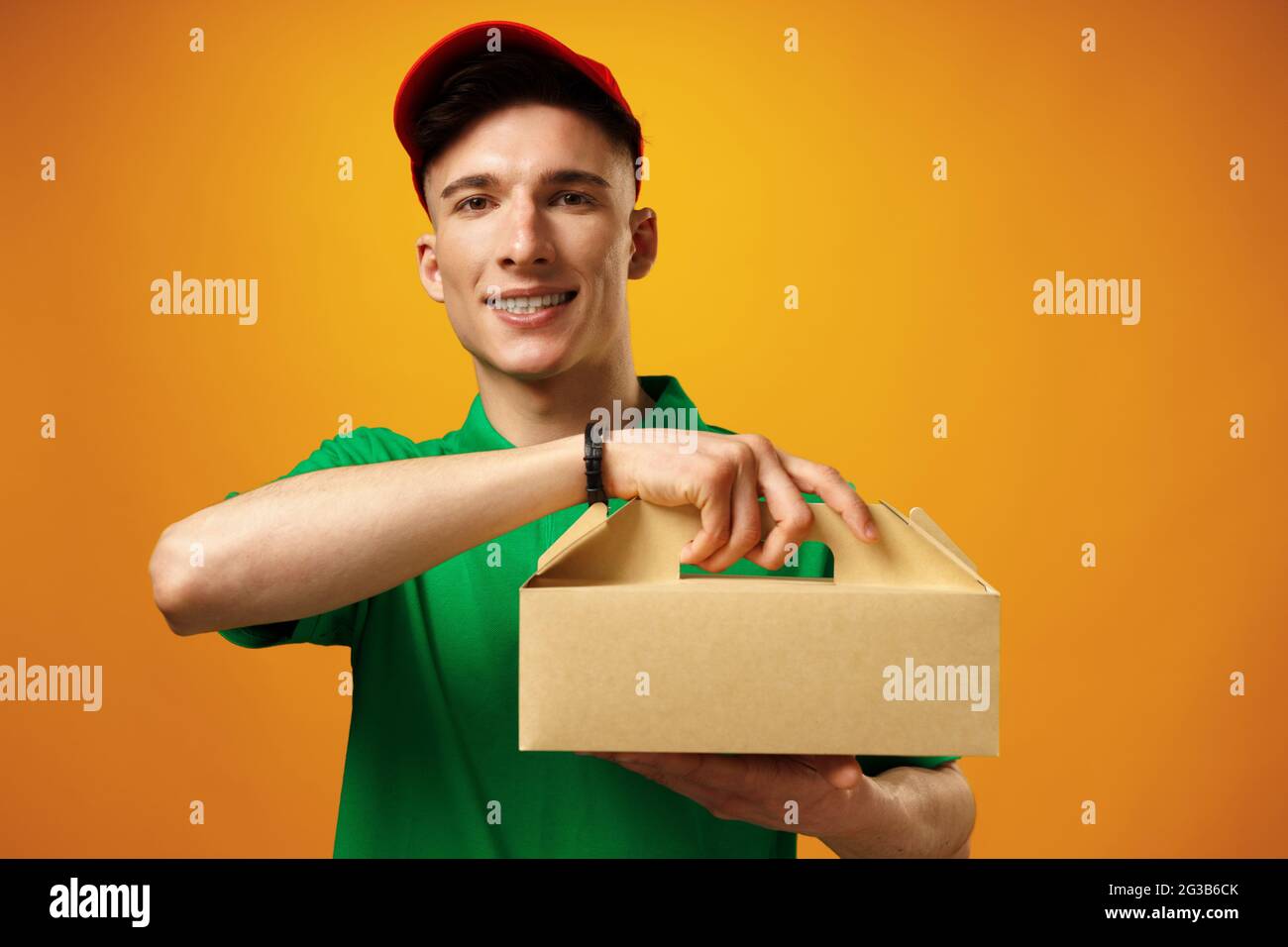 Delivery person holding parcel with food delivery against yellow ...