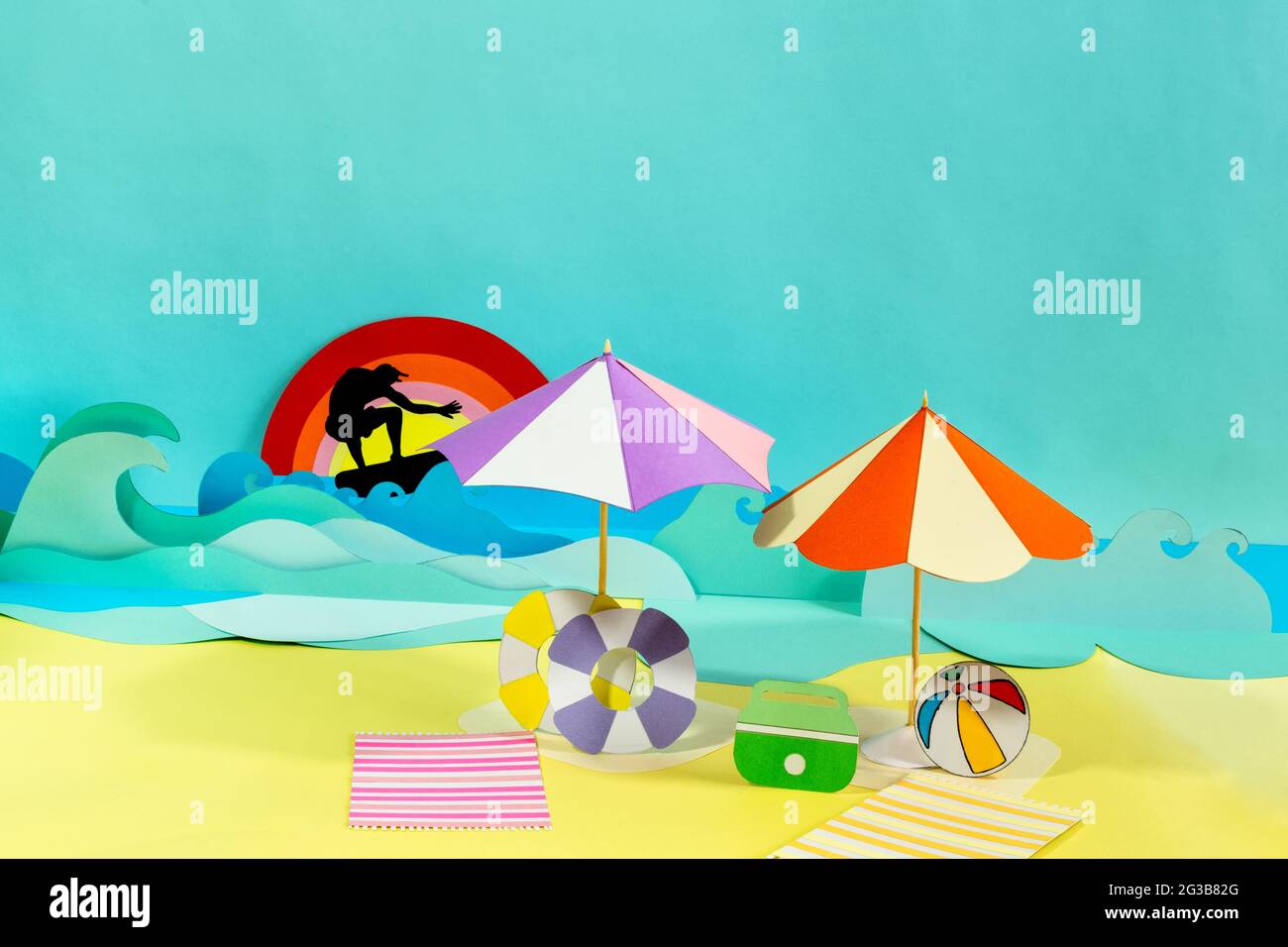 Creative papercraft of a beach, surfboards and a surfer silhouette on ...