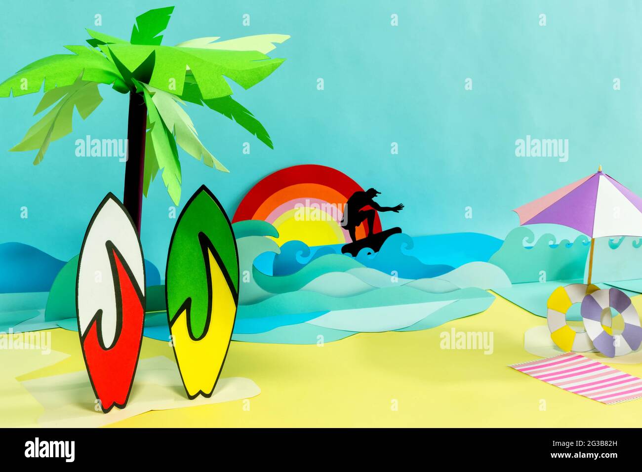 Creative papercraft of a beach, surfboards and a surfer silhouette on ...