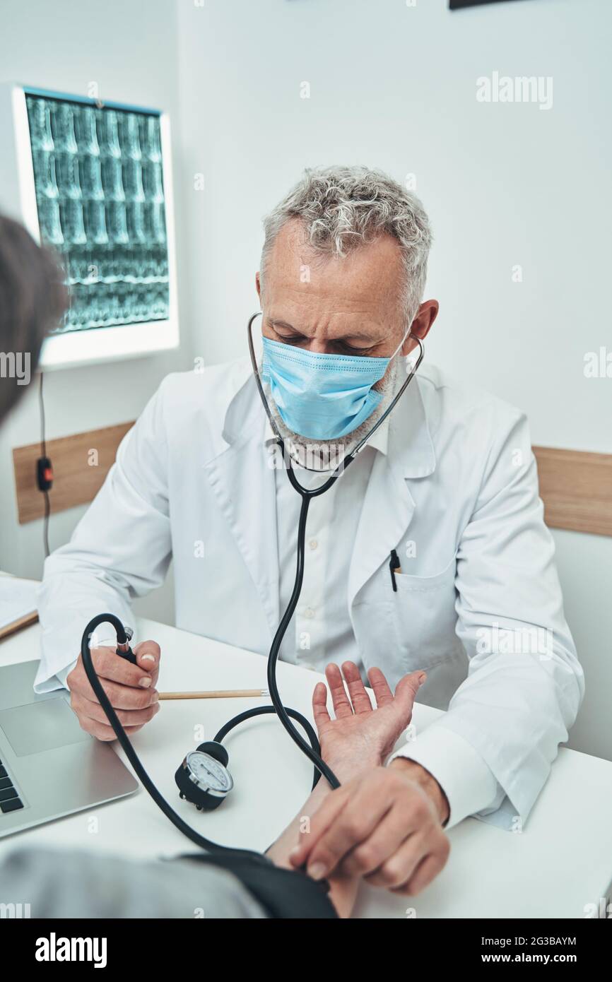 Concentrated physician measuring the patient blood tension Stock Photo ...