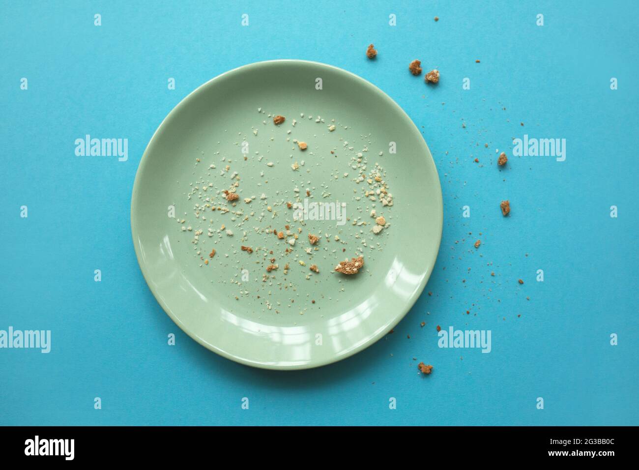 Emty white plate with some crumbs on light blue background. Finished ...