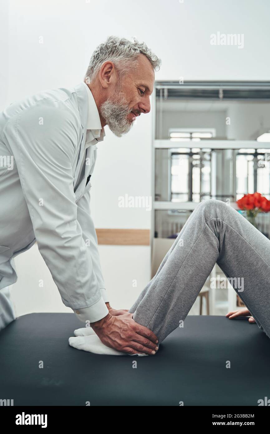 Experienced doctor performing a muscle strength test Stock Photo - Alamy