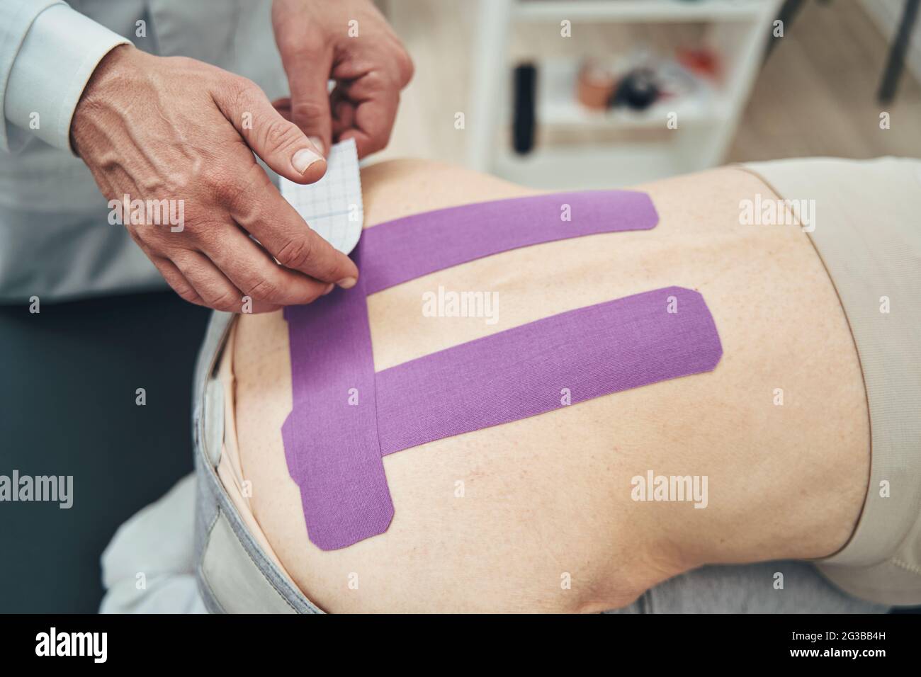Experienced physiatrist using kinesiology taping method for low back ...