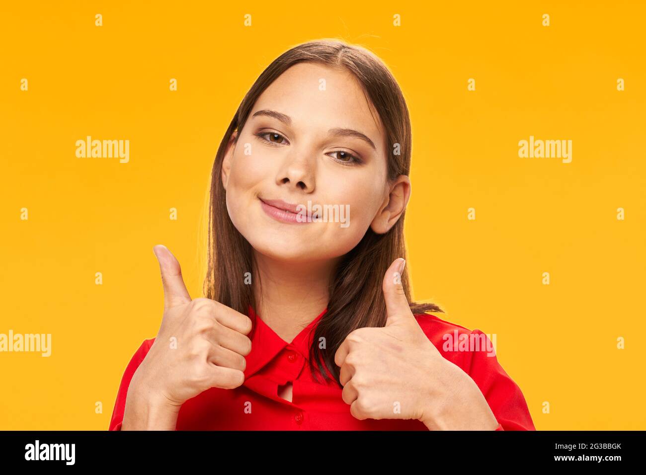 pretty girl showing thumbs up smile close-up yellow background Stock ...