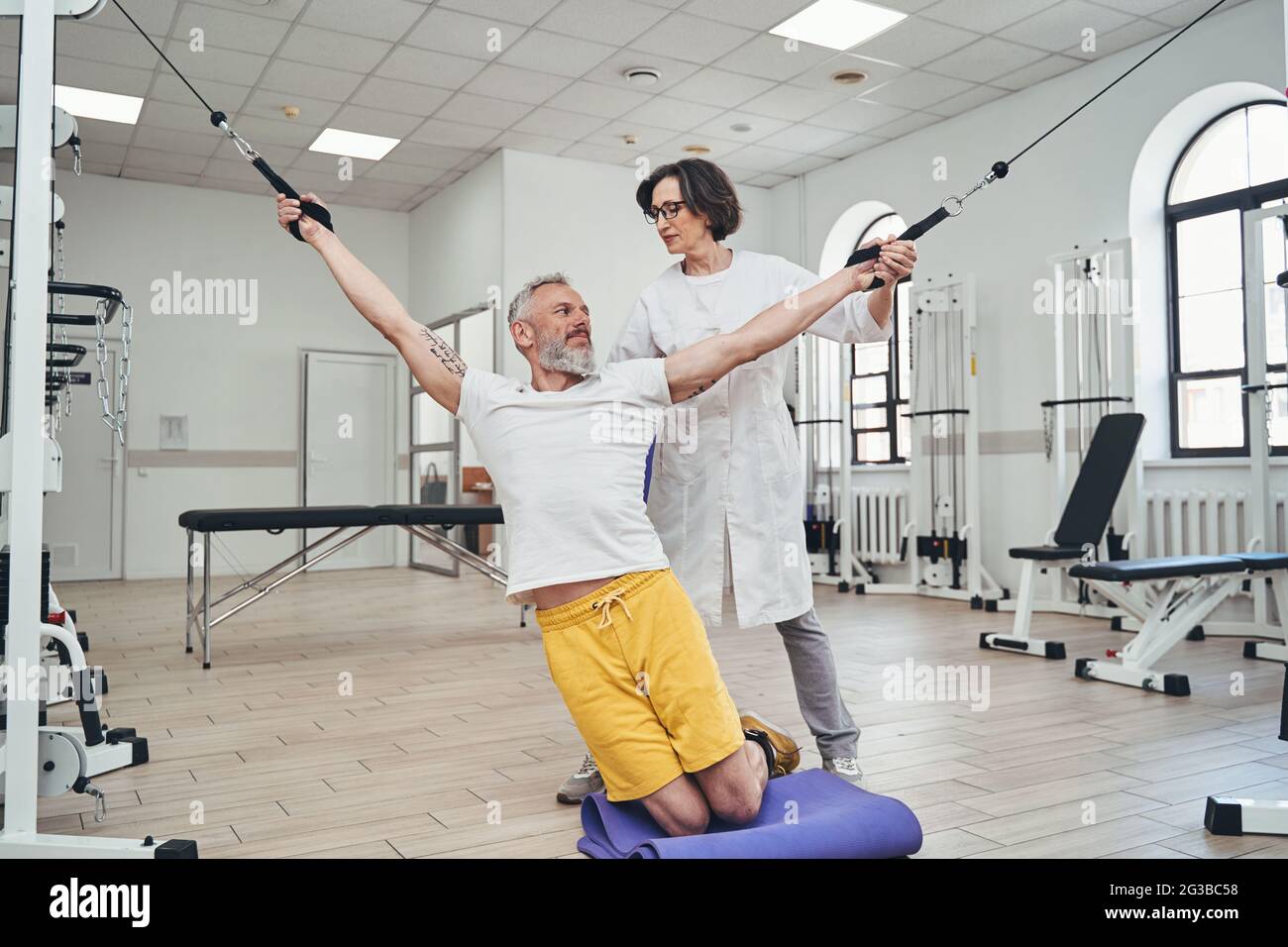 Sportsman performing a stretching exercise using a cable machine Stock ...