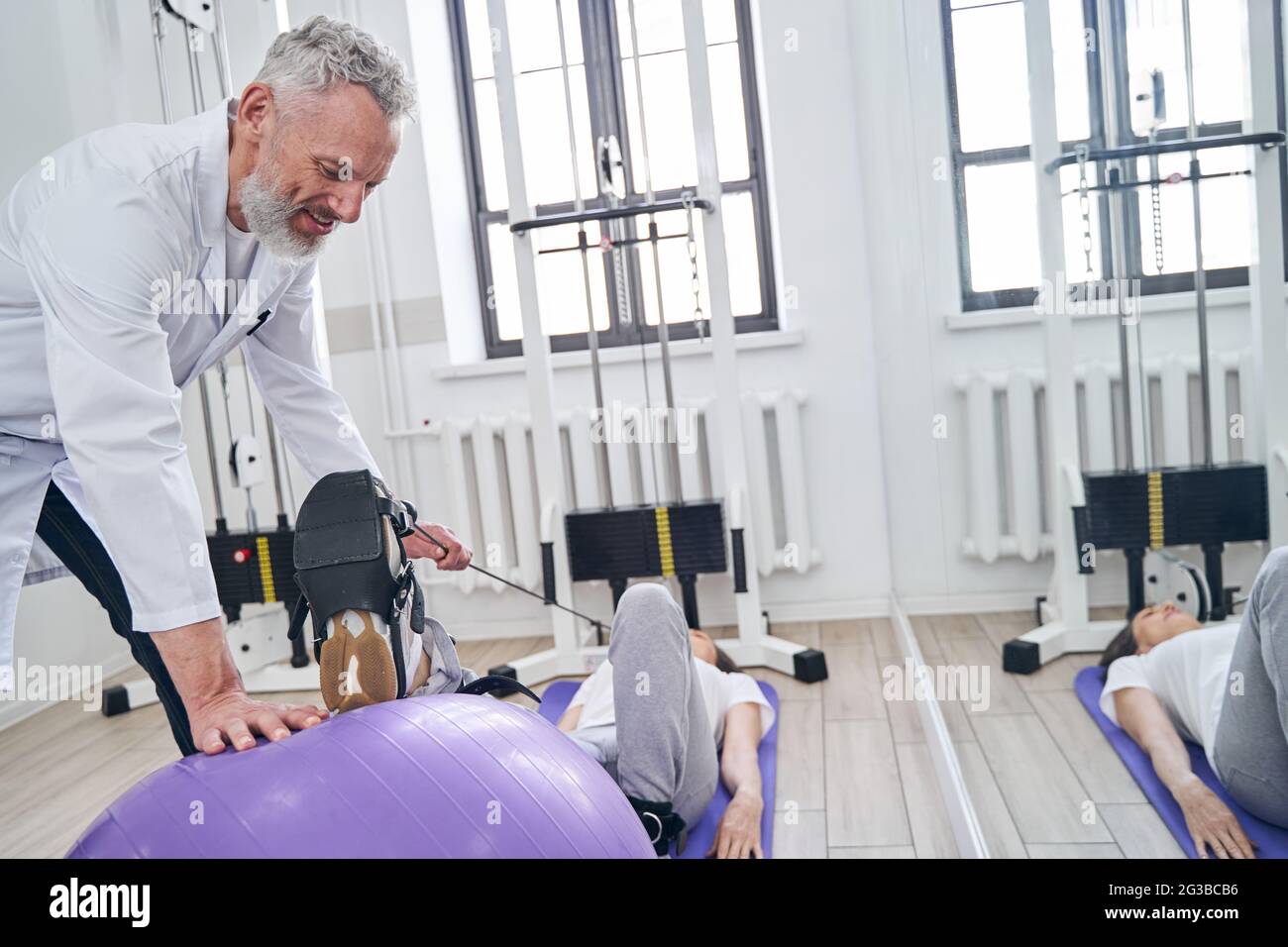 Female doing the strength training exercise assisted by a ...