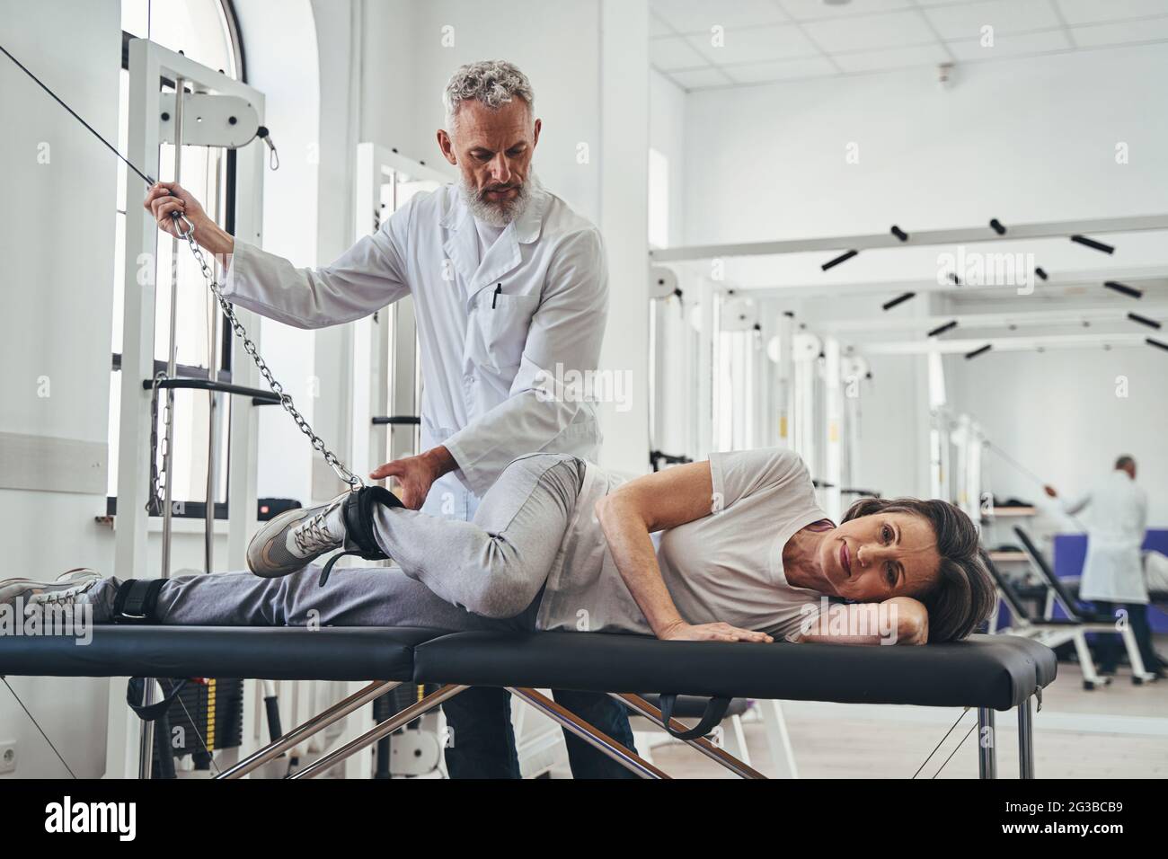 Doctor rehabilitating a patient after the leg injury Stock Photo - Alamy