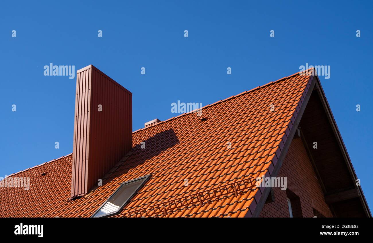 Red corrugated metal profile roof installed on a modern house. The roof ...