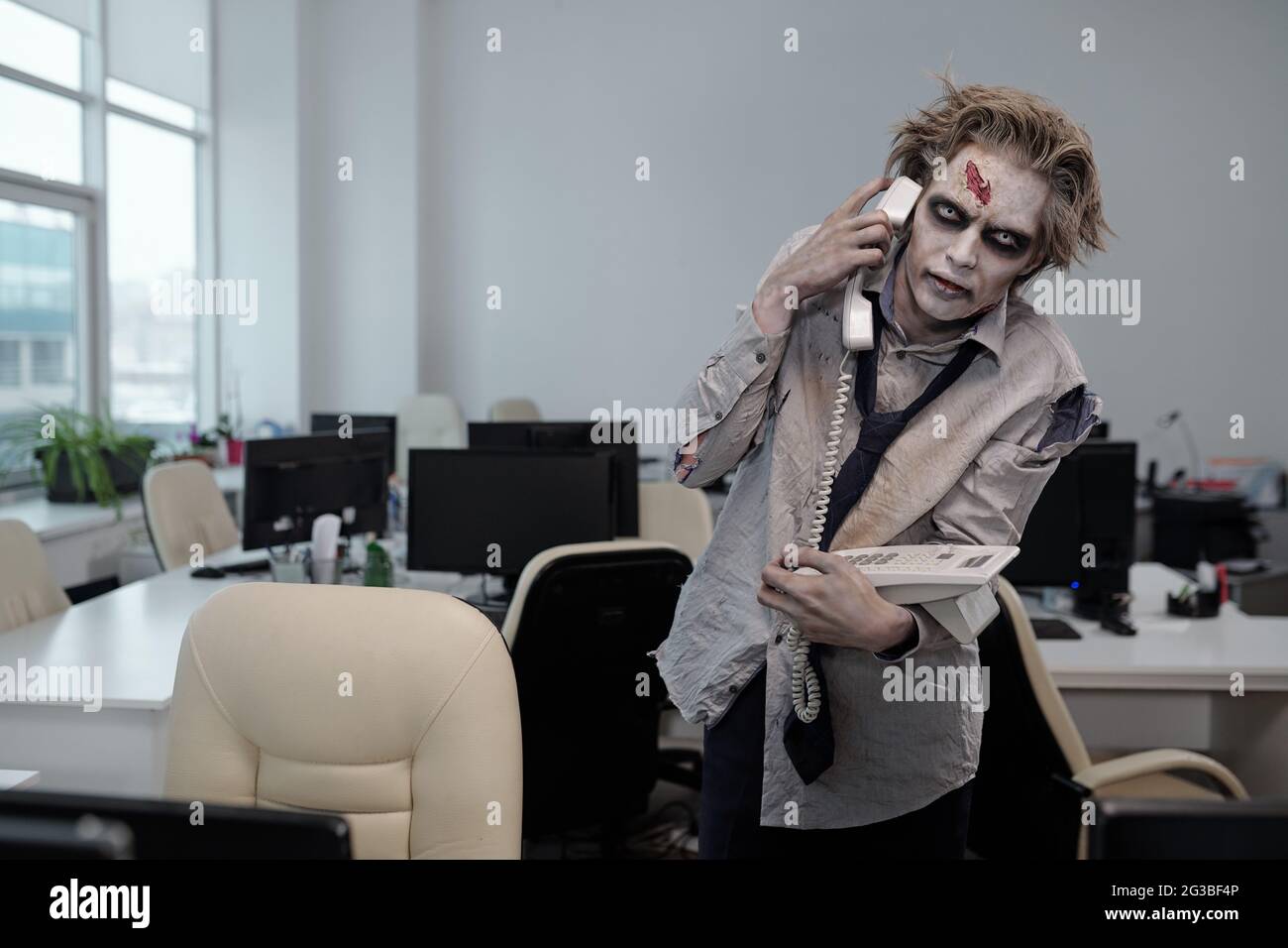 Businessman with zombie makeup speaking on the phone in office ...