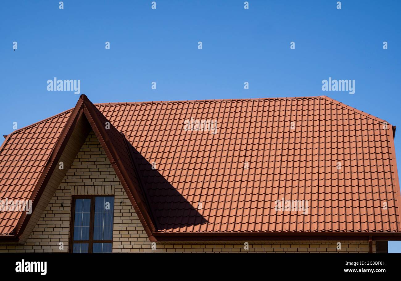 Red corrugated metal profile roof installed on a modern house. The roof ...