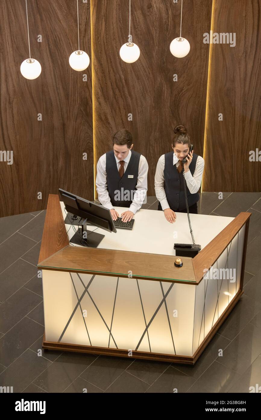 Young hotel reception managers in uniform working by counter Stock ...