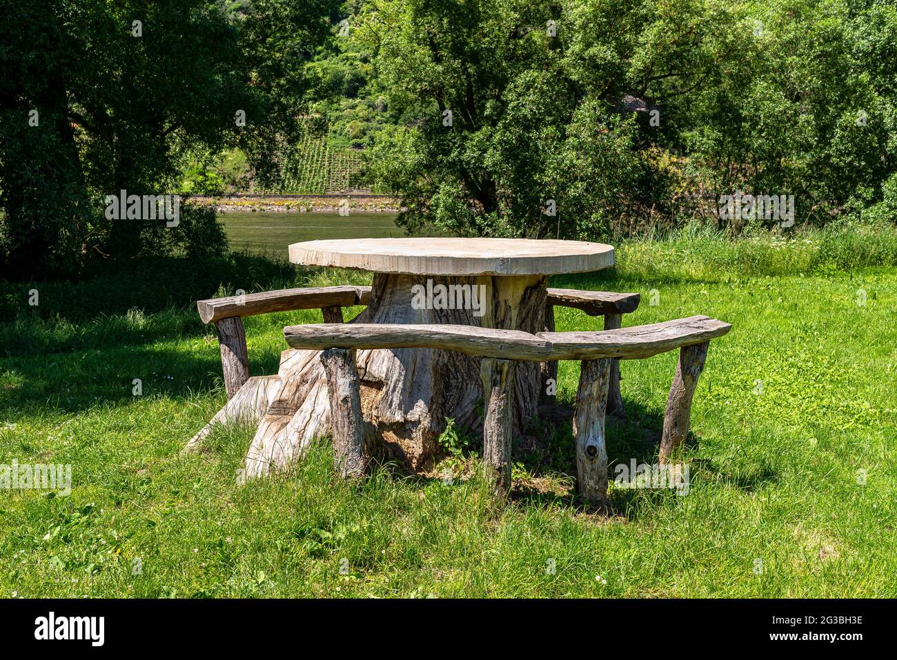 A table made of a tree trunk with a concrete top and wooden seats ...