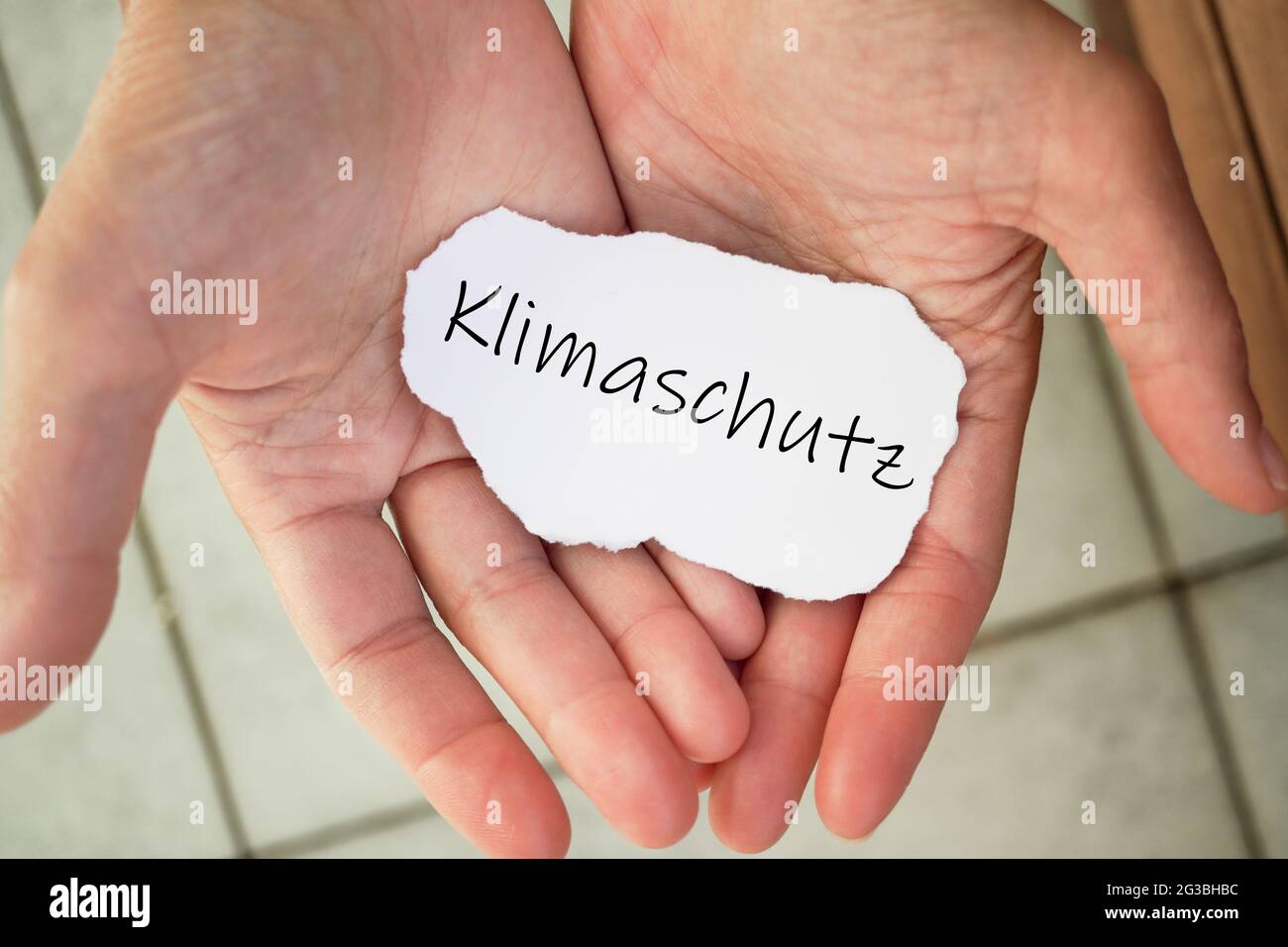 Top view of two hands holding a piece of paper with a text klimaschutz ...
