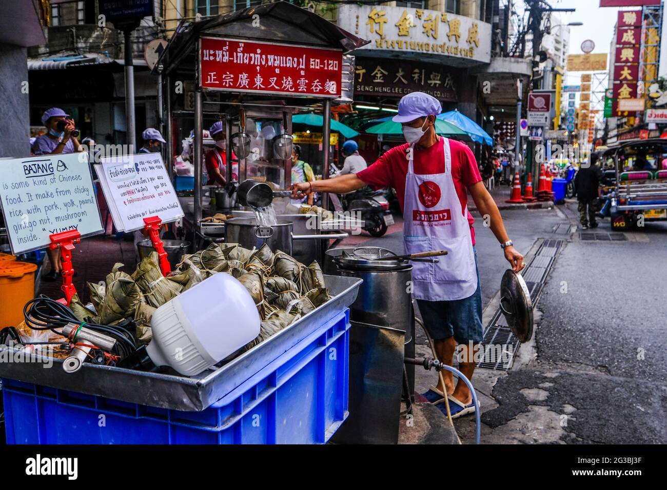 A male street food vendor works at his food stand in Chinatown, Bangkok ...