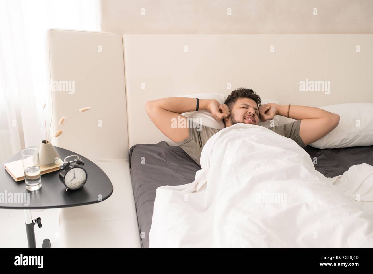 Happy young man stretching in bed after good sleep Stock Photo - Alamy